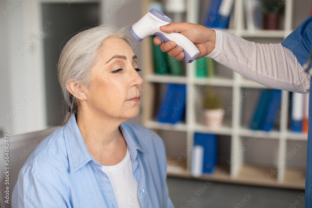 Doctor measures temperature with non-contact thermometer of old ...