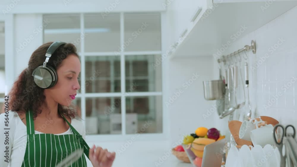 Vidéo Stock A black African American woman wears headphones and cooks ...