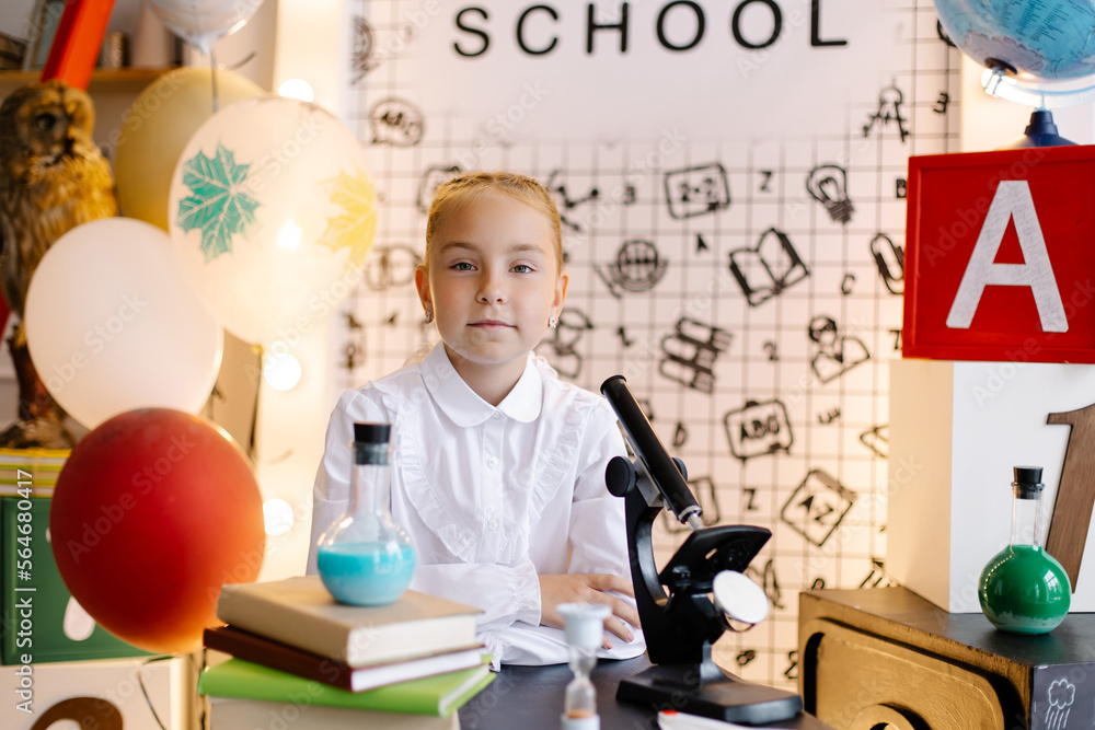 Schoolgirl in the lesson with a microscope. Smart child is learning ...