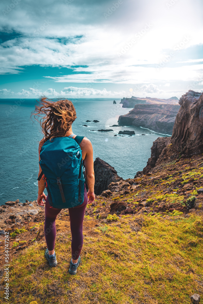 Backpacker woman enjoys panoramic view from a steep cliff overlooking ...