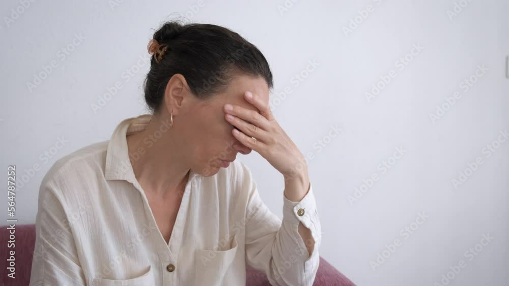 Suffering female rubs against temple. A depressed female rubs her ...