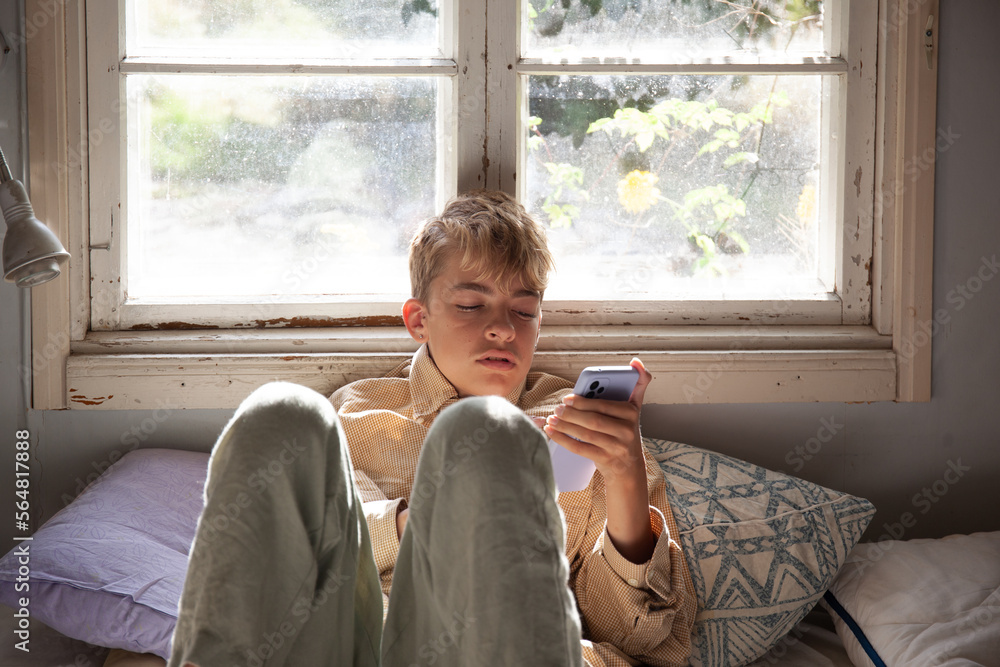 Boy on his phone by window Stock Photo | Adobe Stock