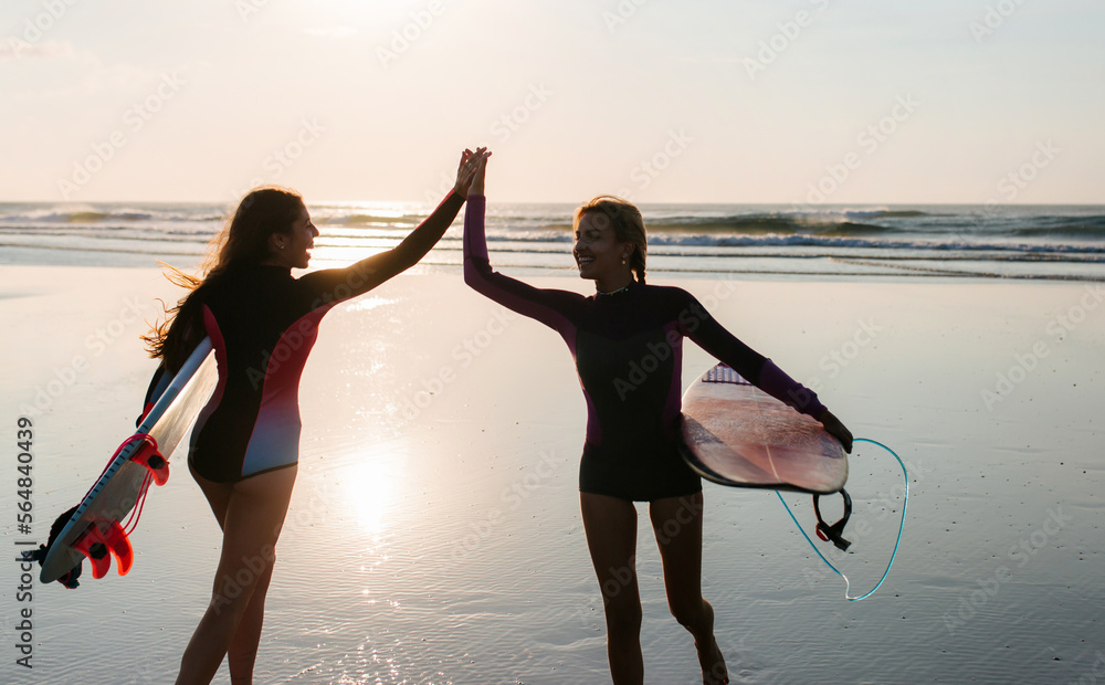 Female surfers giving high five Stock Photo | Adobe Stock