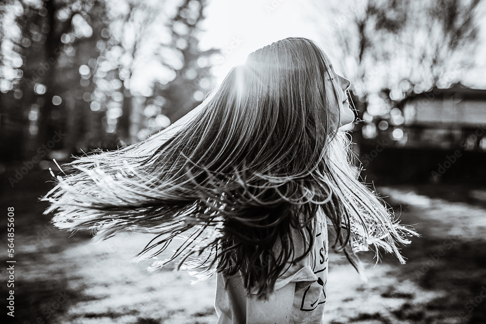 Young girl swinging long hair in backlight Stock Photo | Adobe Stock