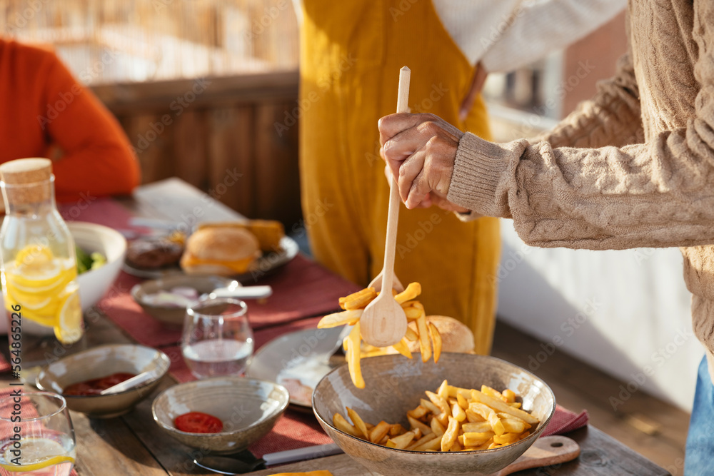 Crop man serving fries on dinner with friends Stock Photo | Adobe Stock