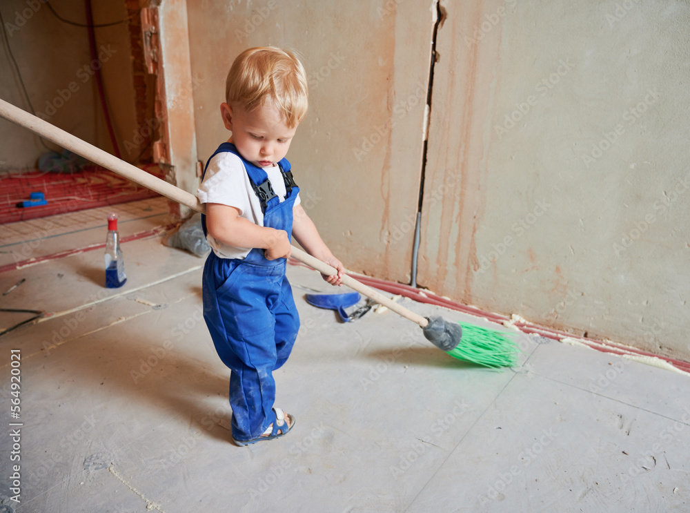 Foto de Full length of child in work overalls sweeping floor with ...