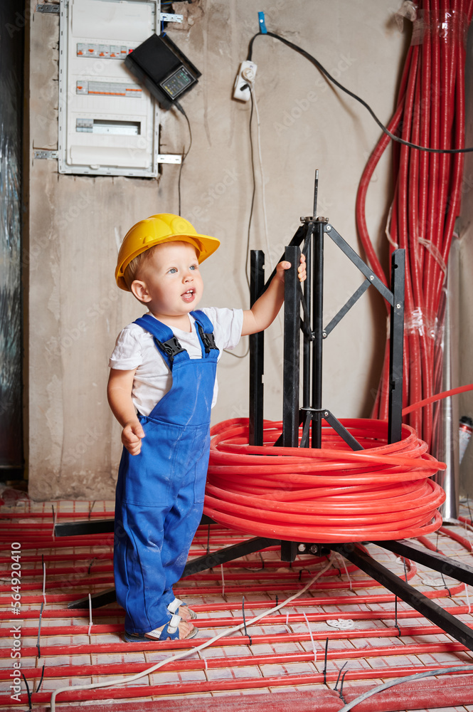 Adorable little boy standing near underfloor heating pipes. Cute kid ...