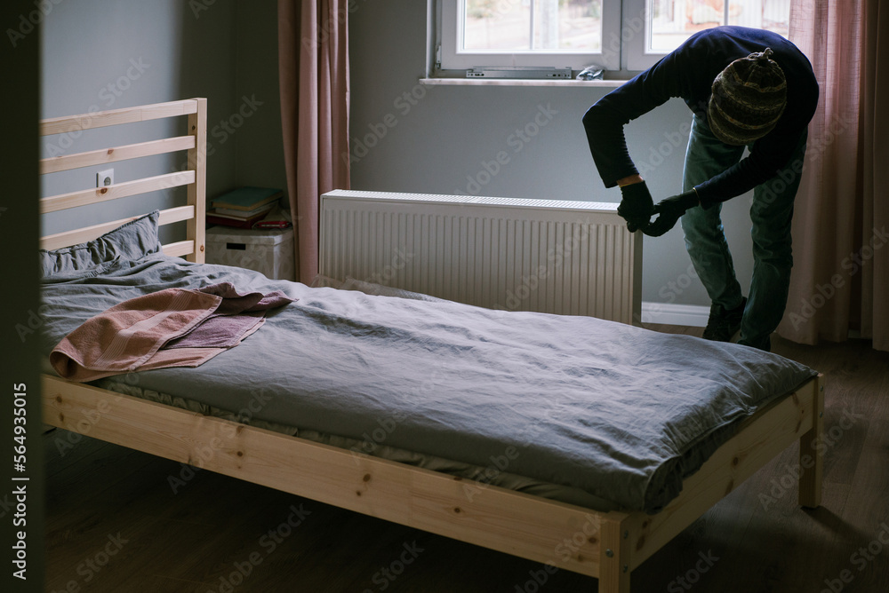 Adult man unpacking new heating radiator next to wooden bed Stock Photo ...