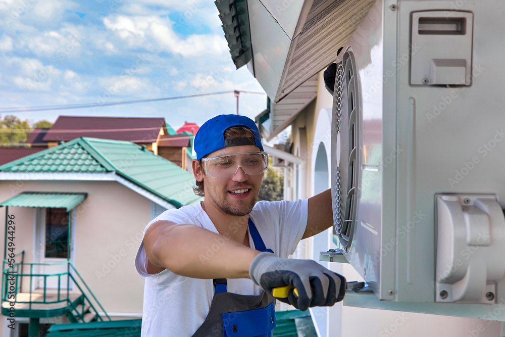 An experienced installer professionally twists the air conditioner ...