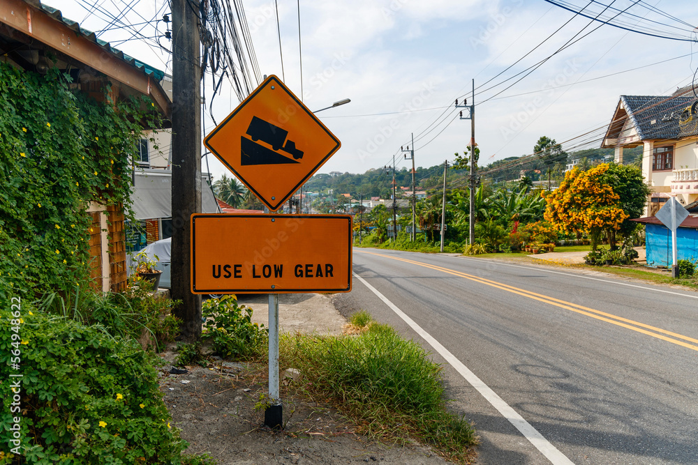 A road with sharp corner and sign for trucks to use low gear, with the ...