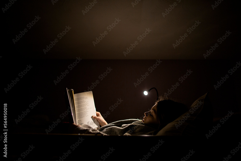 Young girl reading before bedtime in bed with lamp Stock Photo | Adobe ...