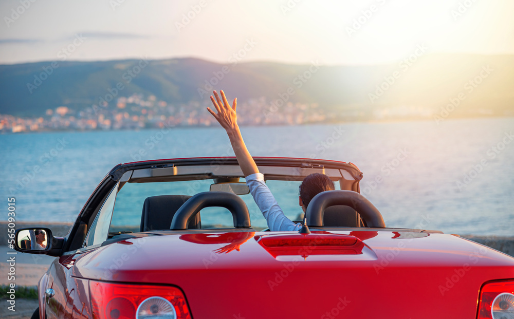 Foto de Woman in red car with open roof at background of sea water ...