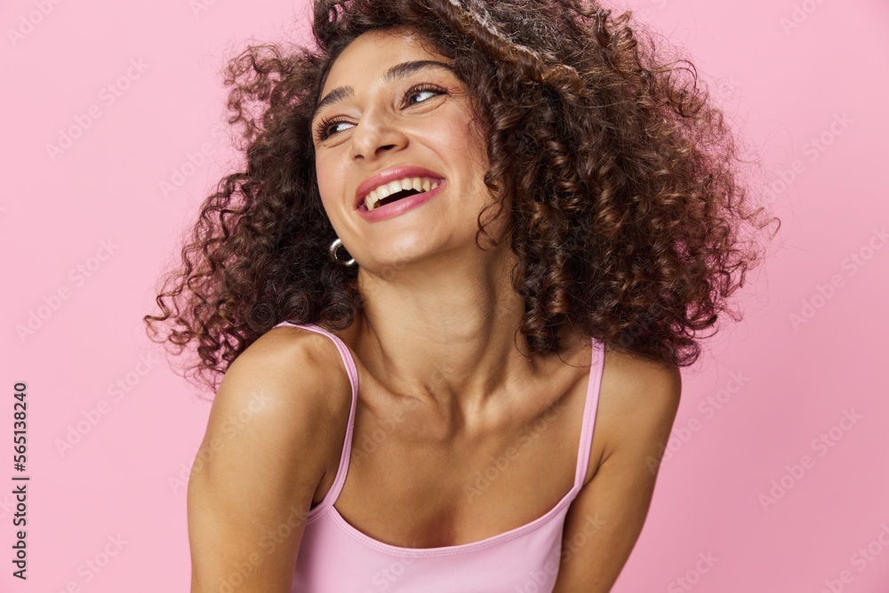 Woman with curly afro hair model poses on a pink background in a pink T ...