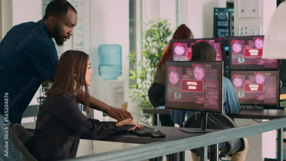 Diverse group of engineers having computer hacked and system crash on multiple monitors, reading ...