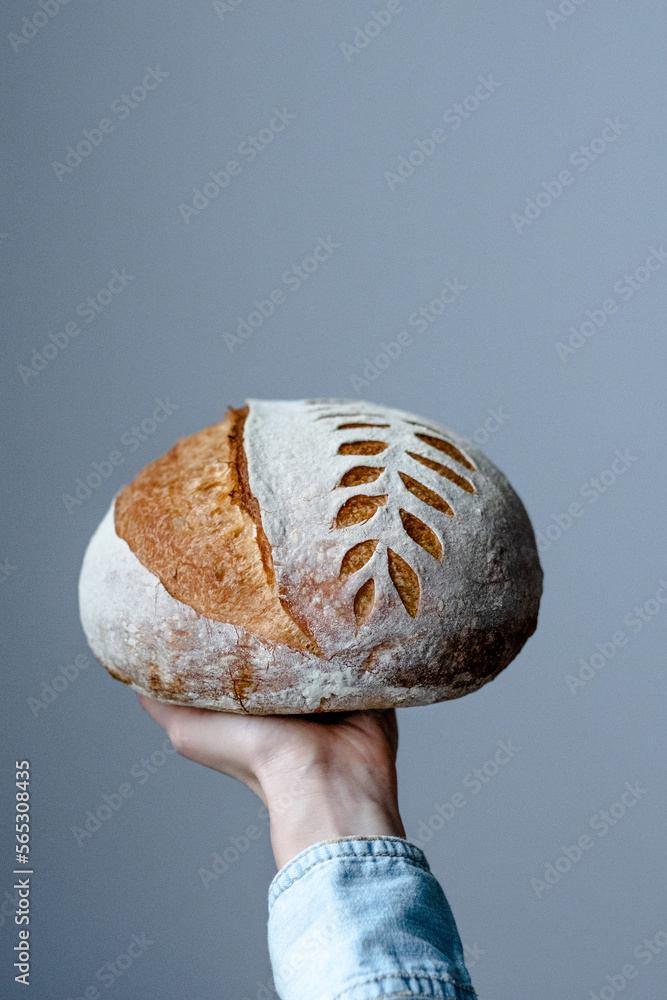 Scoring a bread pattern in the hand of an artisan on a gray background ...