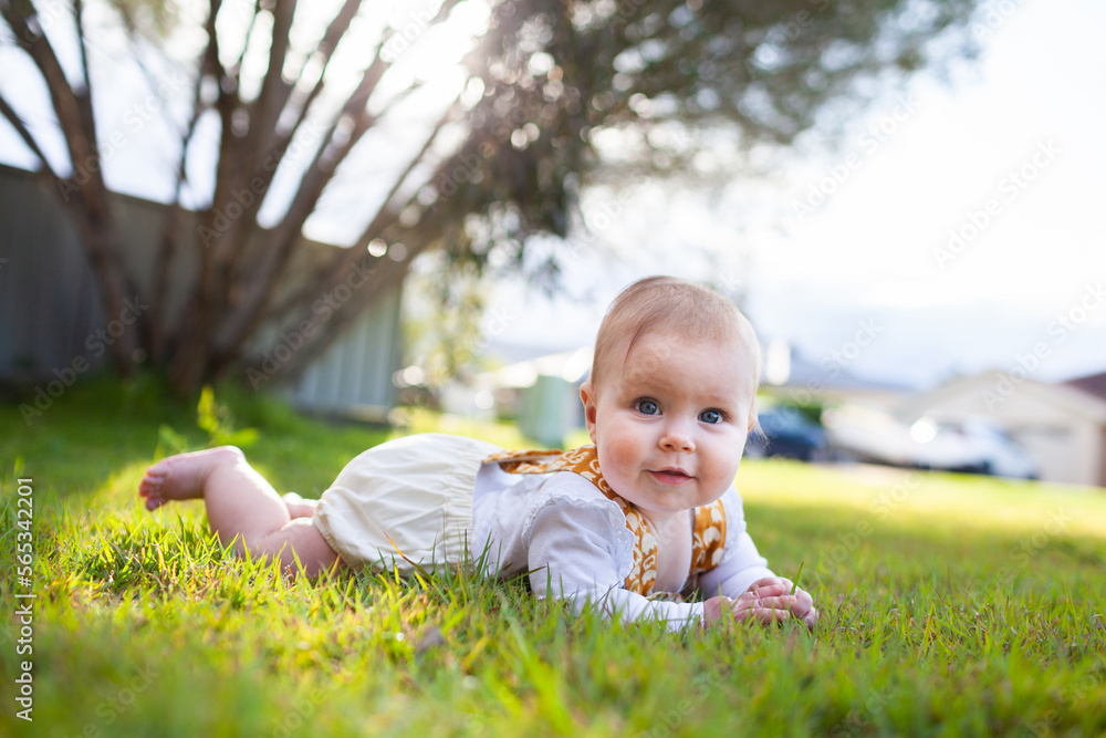 baby girl lying on grass outside in front garden of suburban home Stock ...