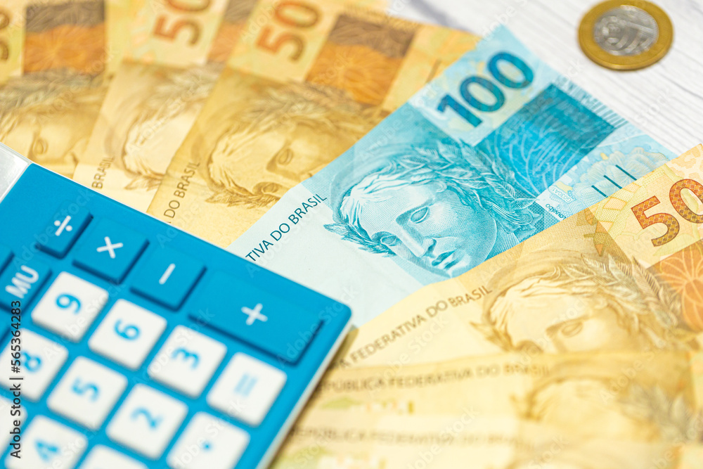 Notas do Real Brasileiro sobre uma mesa de madeira com uma calculadora ...