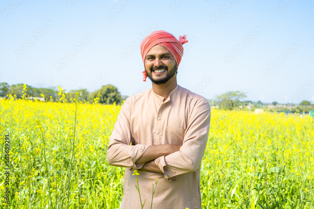 Happy smiling young farmer standing with crossed arms by looking camera ...