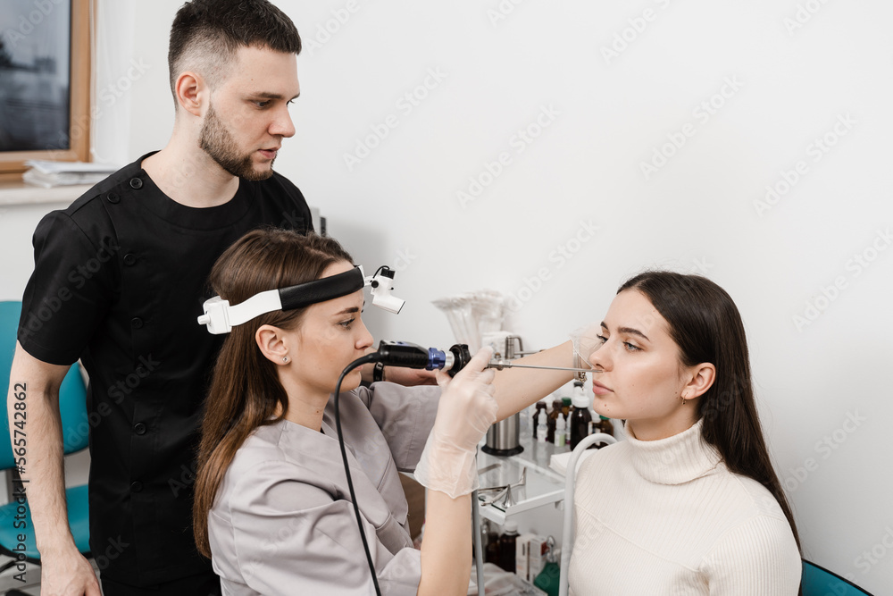 ENT otolaryngologist colleagues with headlight treat nose woman patient ...