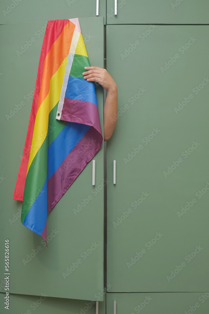 Hand holds to hide rainbow flag back inside closet. Fear of coming out ...