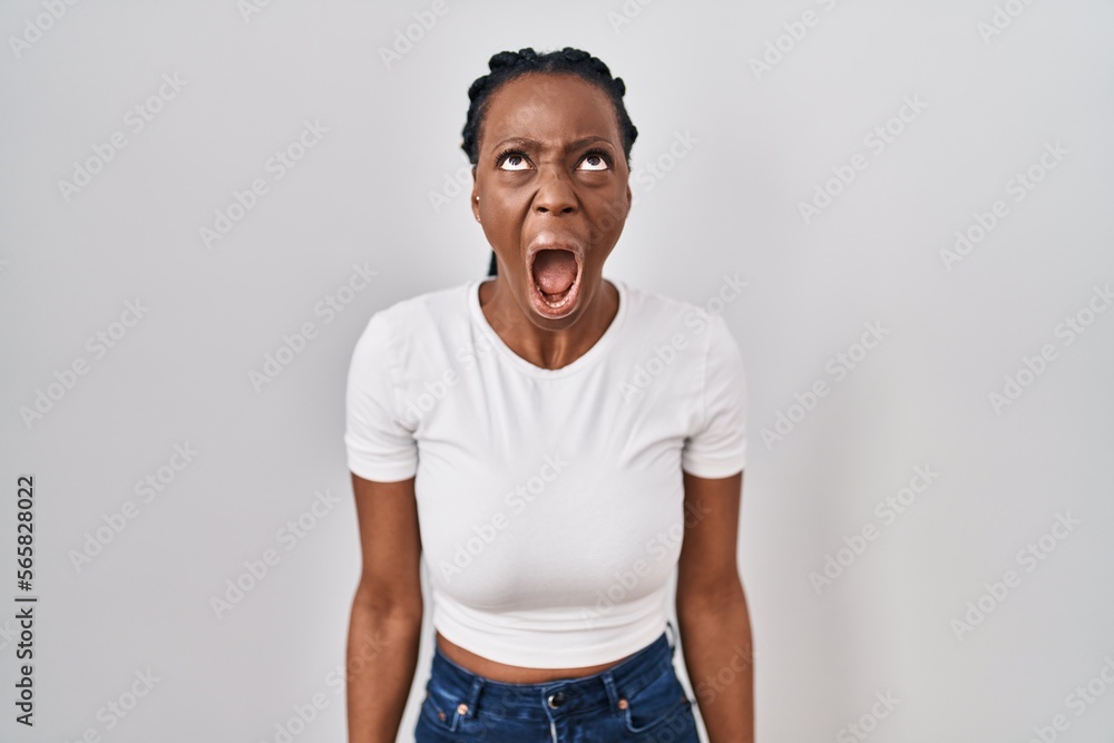 Beautiful black woman standing over isolated background angry and mad ...