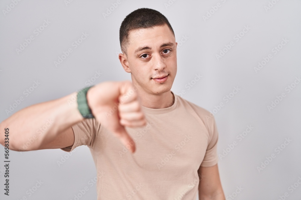 Young man standing over isolated background looking unhappy and angry ...