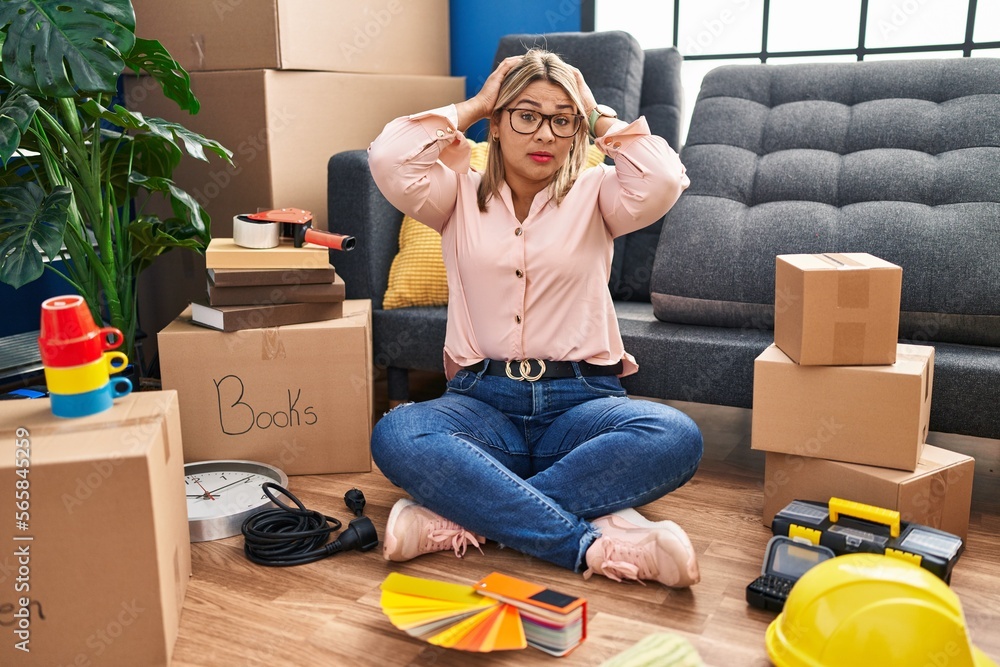 Young hispanic woman moving to a new home sitting on the floor crazy ...