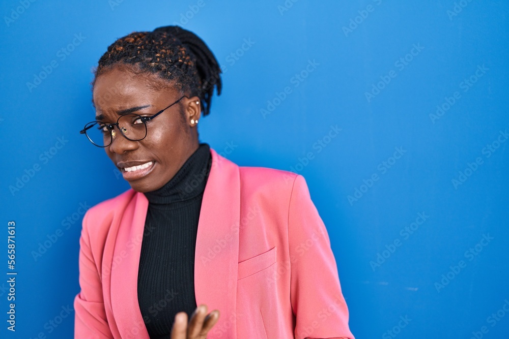 Beautiful black woman standing over blue background disgusted ...