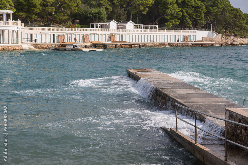 Stormy sea with splashing waves at a landing stage opposite to a beach ...