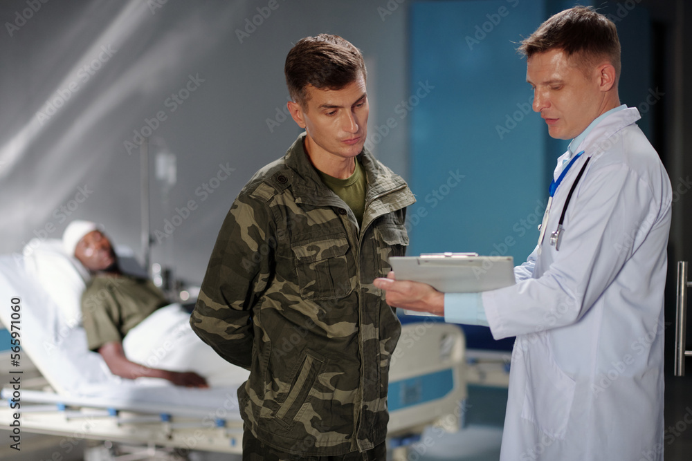 Doctor showing medical test results to sergeant of injured soldier ...