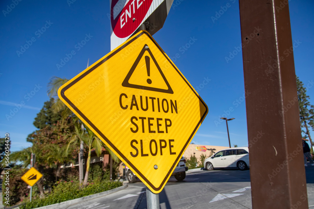 Yellow sign with graphic and exclamation point indicating a steep slope ...