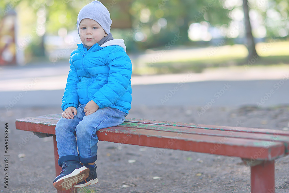 boy child is sitting on a park bench walking Stock Photo | Adobe Stock