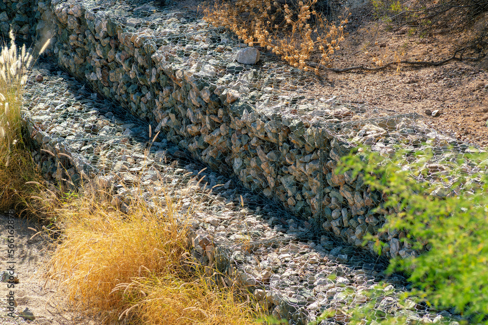 Stock retaining wall with metal mesh wires and large rocks stacked in ...