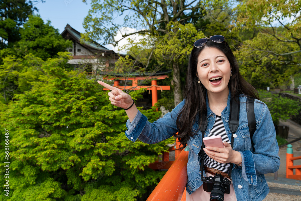 smiling asian Japanese girl traveler looking at camera while pointing ...