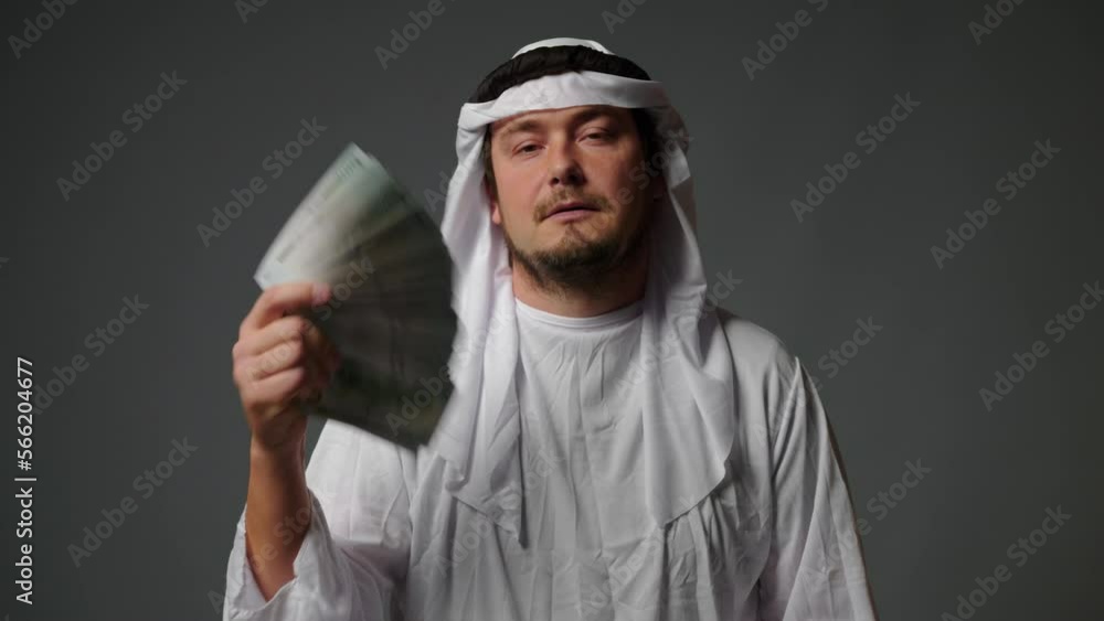 Successful Arabic sheikh in traditional clothes holds money in his ...