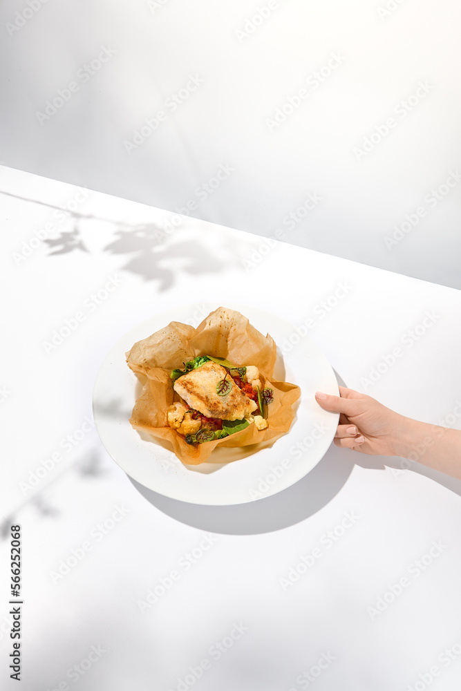 Female hand holding fish dish. Roasted fish in hand of person. Food ...