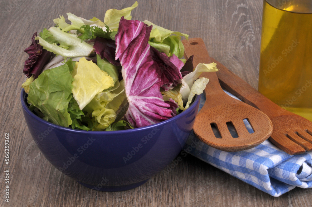 Bol avec un mélange de salades avec des couverts en bois et une ...