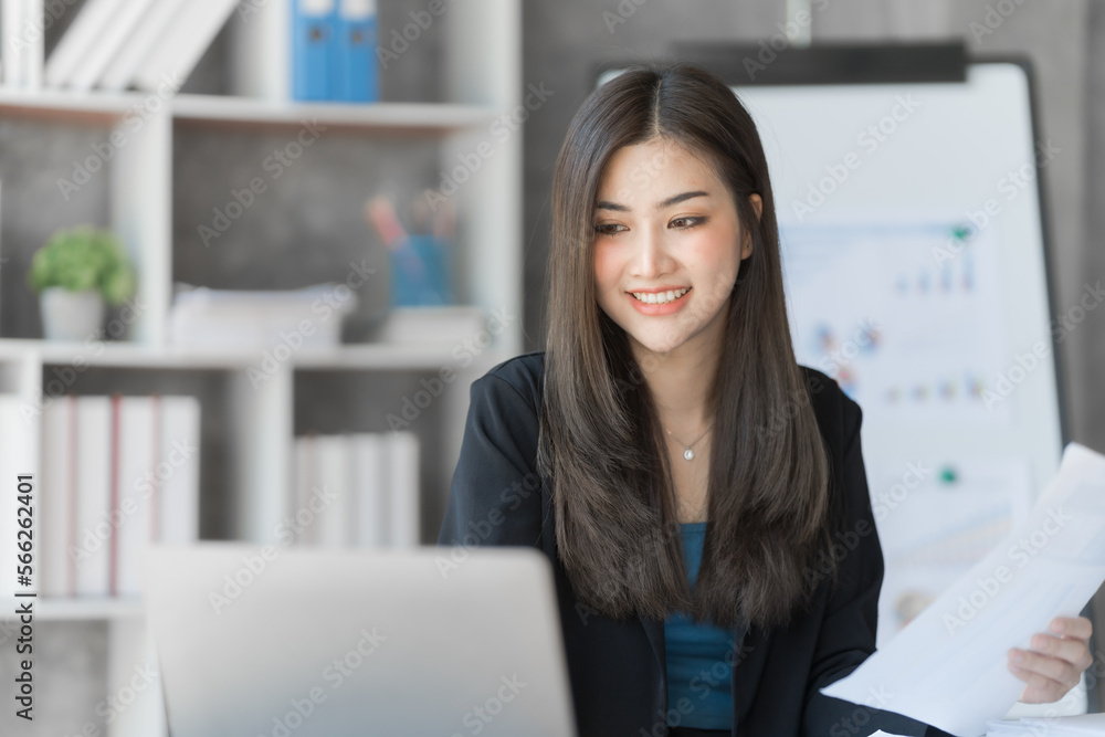 Beautiful Asian female bookkeeper doing online accounting with laptop ...