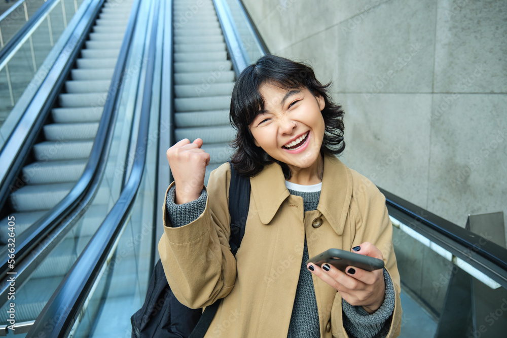 Joyful And Positive Korean Girl Celebrates Looks Surprised Goes Down Escalator With