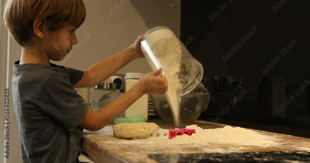 Side view of happy preteen boy playing with flour dough, pouring flour ...
