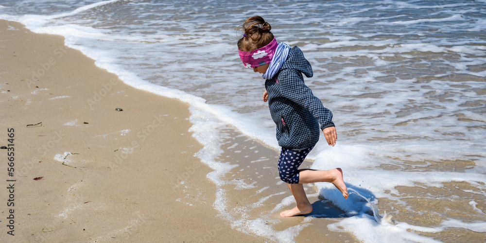 Foto de Kind rennt am Strand durch das Wasser do Stock | Adobe Stock