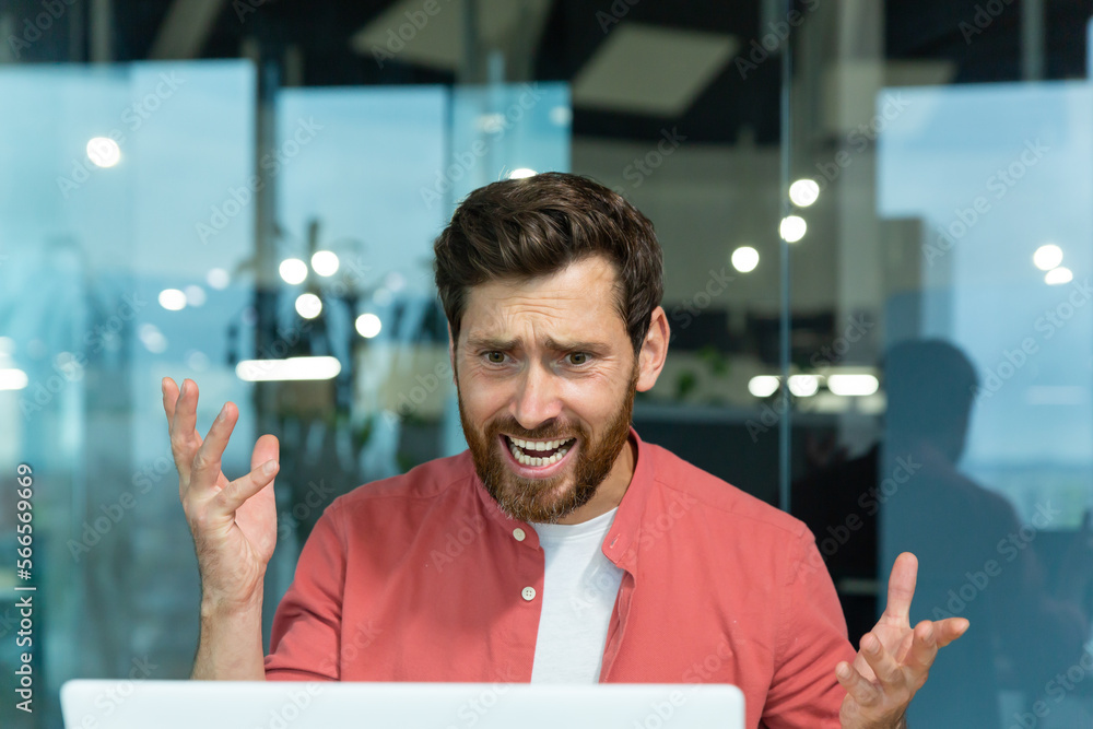 Close up photo. An angry young man in a red shirt is sitting in the ...