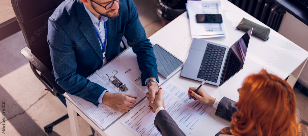 Happy bank manager shaking hands with a client after successful ...