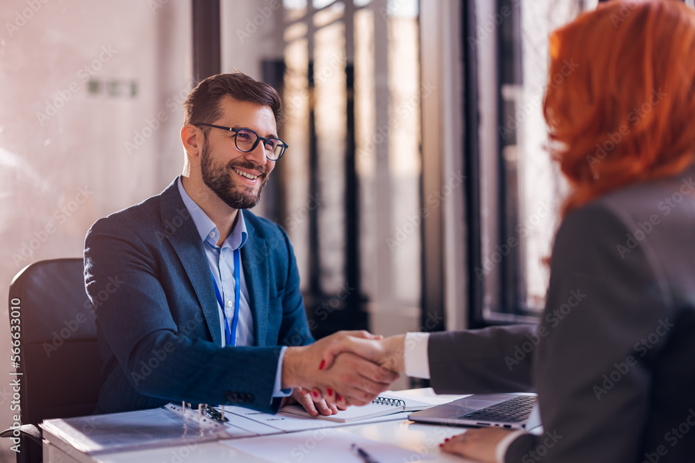 Foto de Happy bank manager shaking hands with a client after successful ...