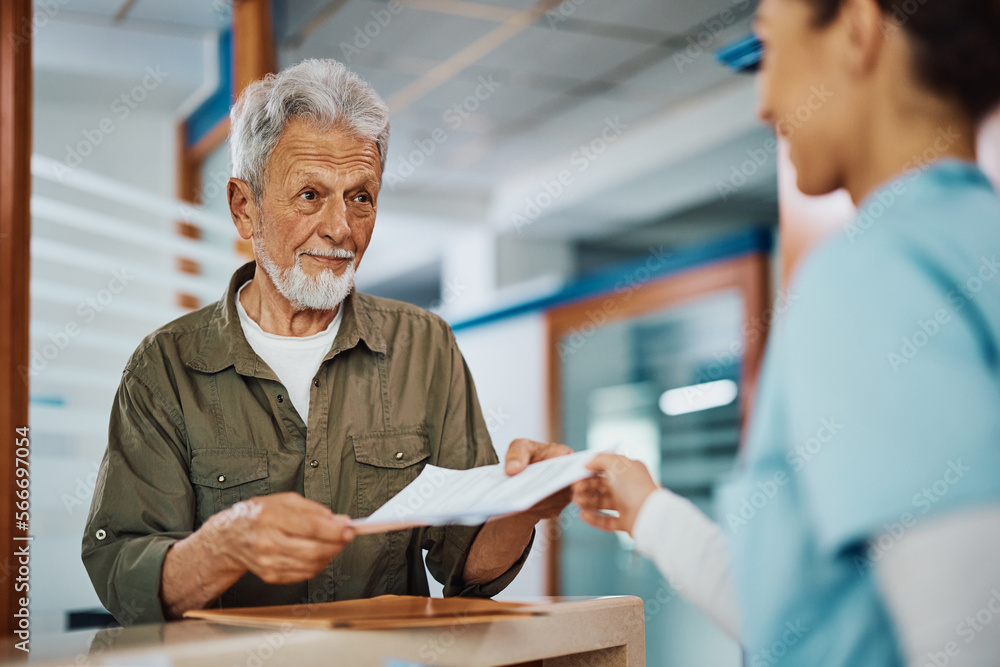 Elderly man receiving his medical documents from nurse at reception ...