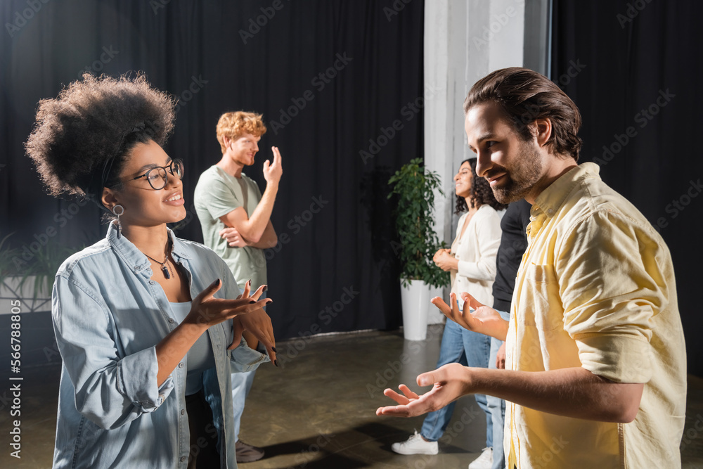 smiling multiethnic actors gesturing during conversation in acting ...