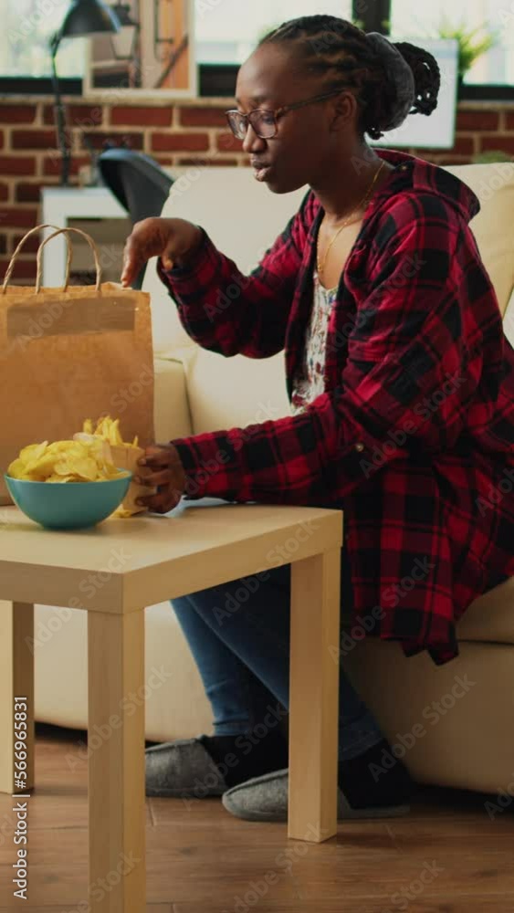 Vertical video: Young adult taking out hamburger and fries, eating fast ...