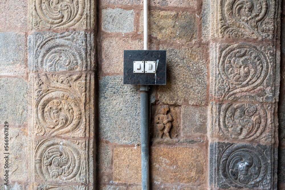 An electric switch board between carved columns on the stone wall of an ...