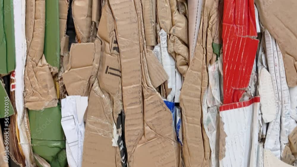 A large stack of waste paper from pressed cardboard boxes is sorted and ...