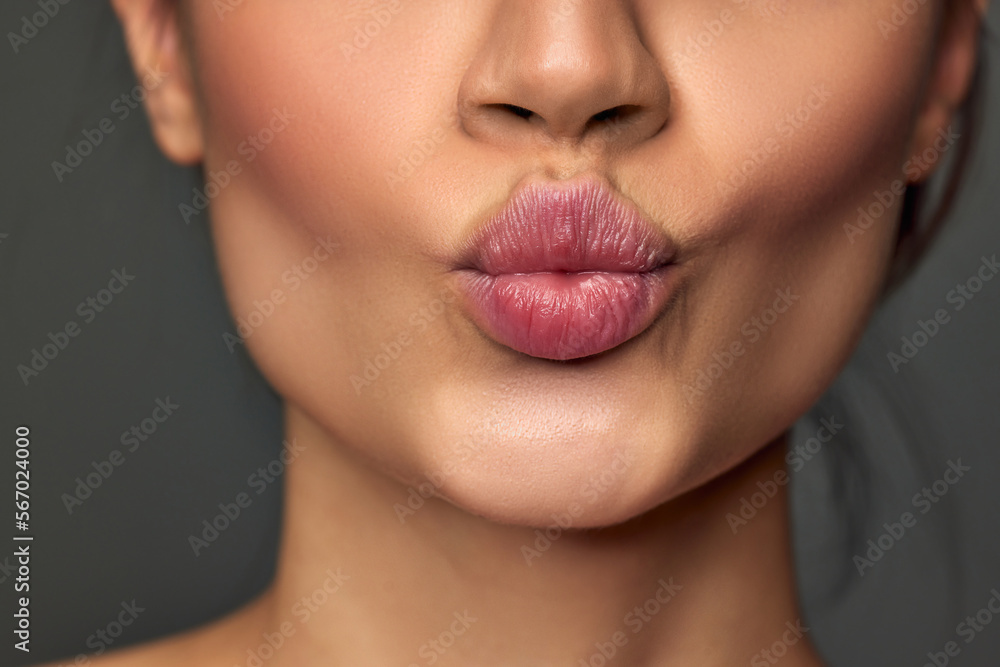 Cropped image of female face, lips, nose, chin on grey studio ...